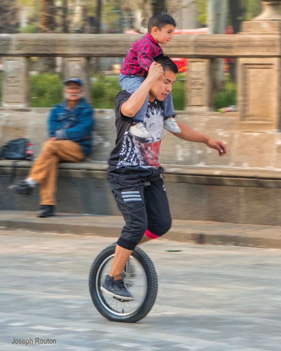 Solve photo of a father giving his son a ride on a unicycle in a park ...